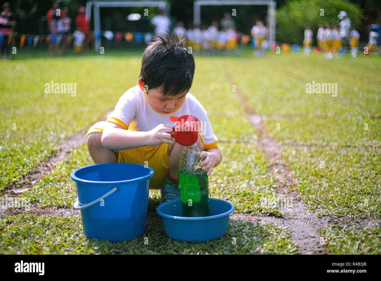 Children compete in fill-the-bottle game during their kindergarten ...