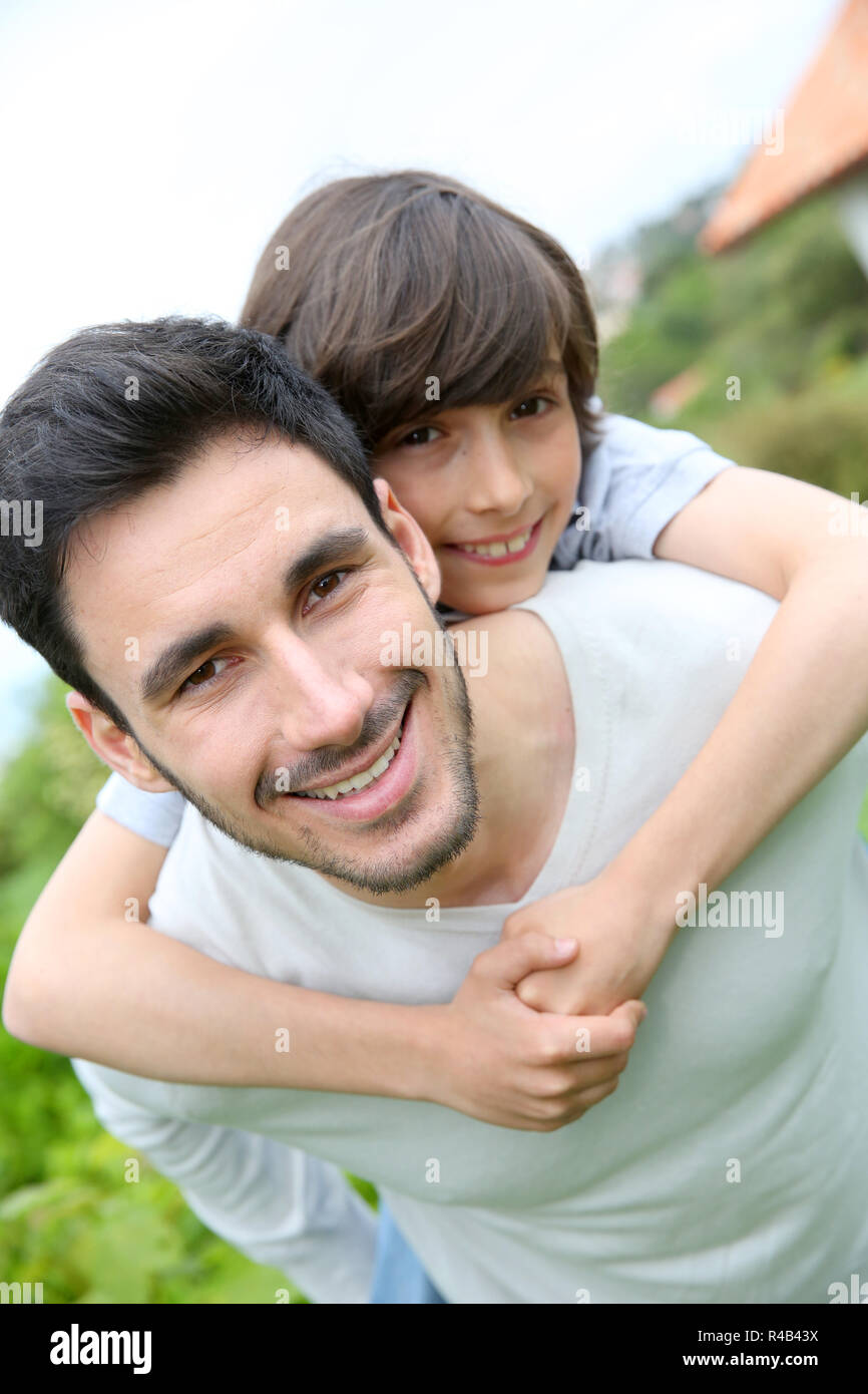 Father giving piggyback ride to his son Stock Photo - Alamy