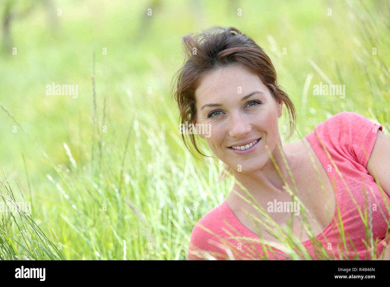 Beautiful smiling woman laying in country field Stock Photo - Alamy