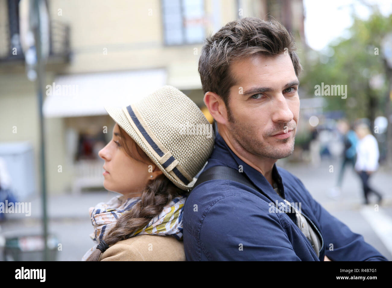 Couple in street leaning back to back Stock Photo - Alamy