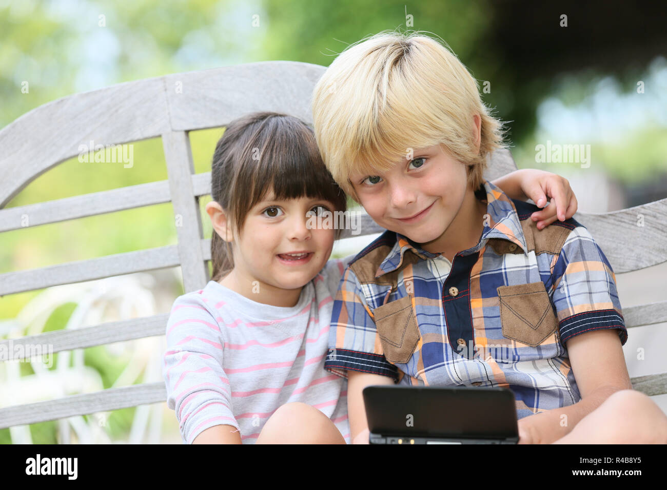 Kids sitting on outdoor bench and playing video games Stock Photo - Alamy