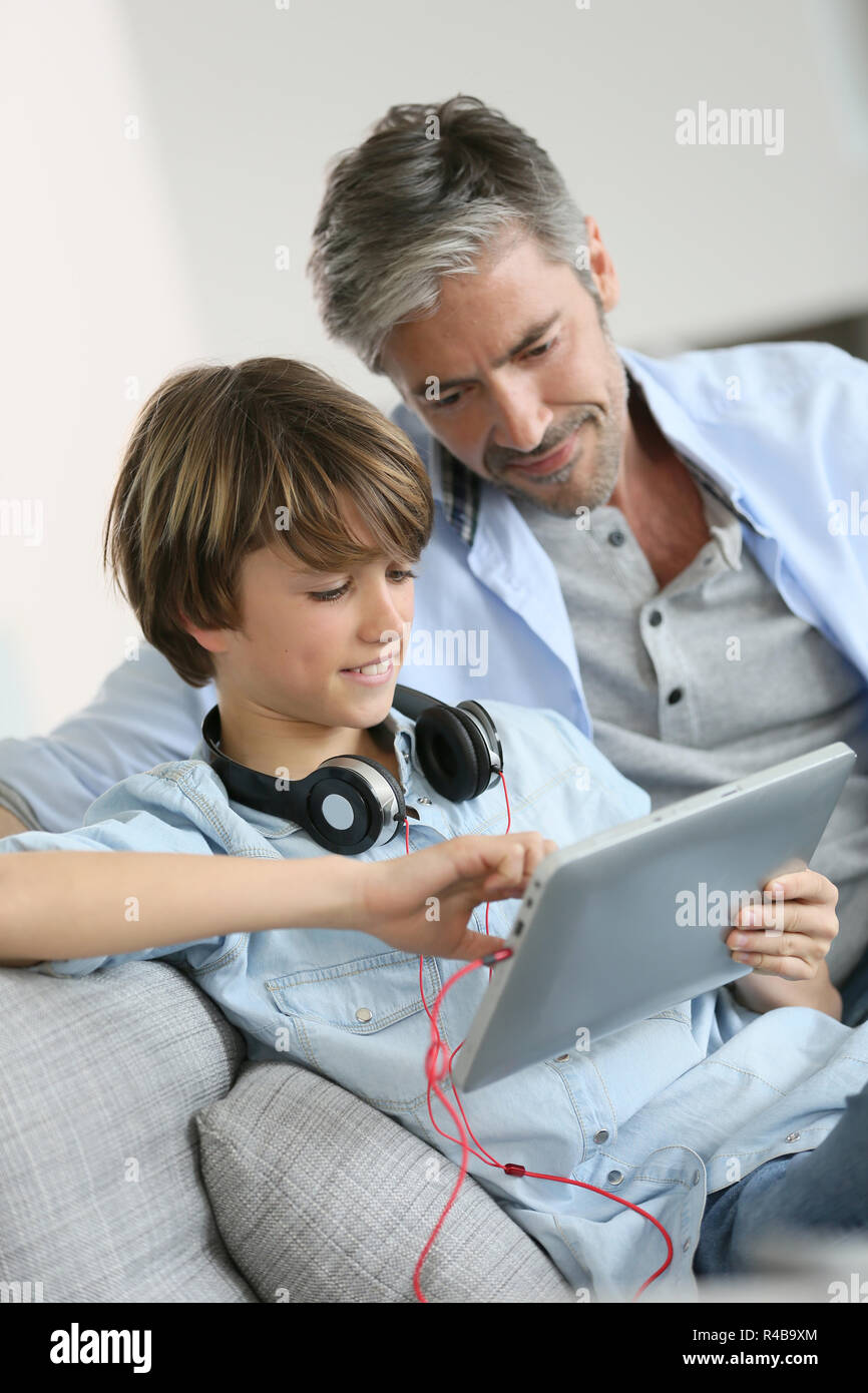Father watching kid playing with tablet Stock Photo - Alamy