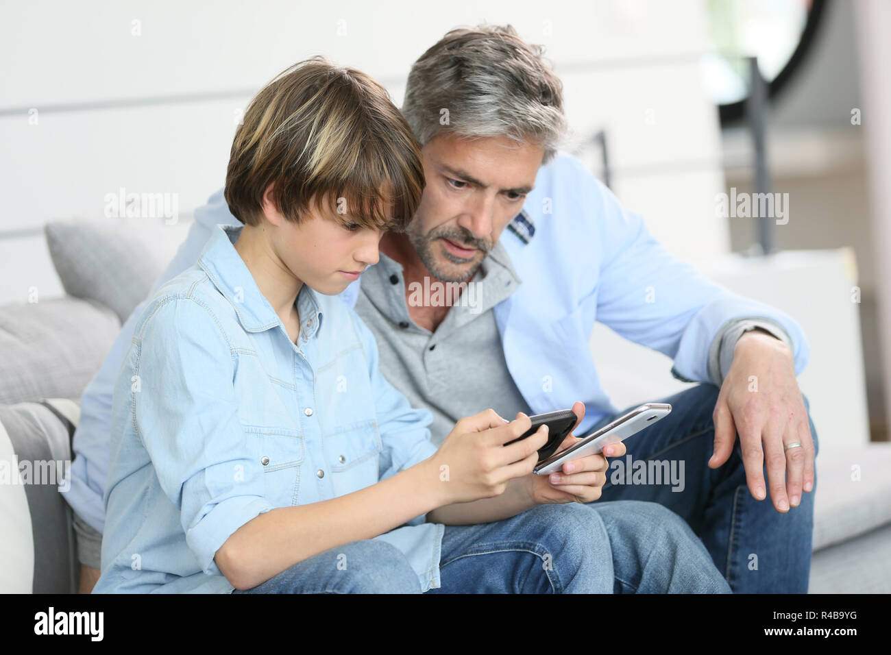 Smiling father son playing smartphone hi-res stock photography and ...
