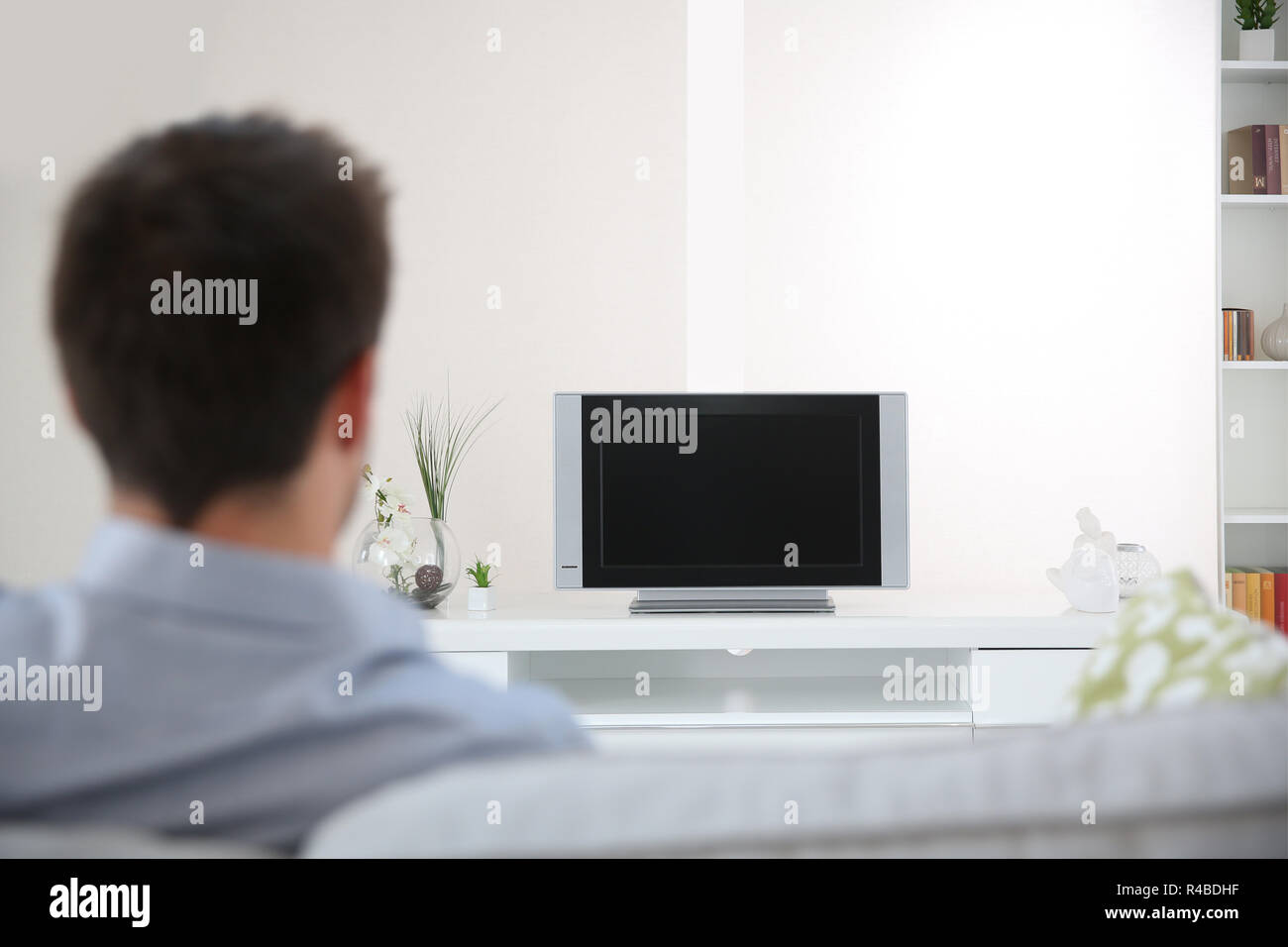 Back view of man in couch watching TV Stock Photo - Alamy