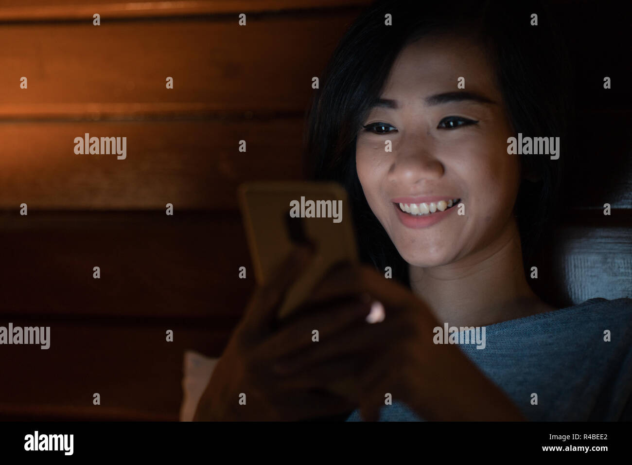 asian woman with smart phone while laying on bed Stock Photo - Alamy