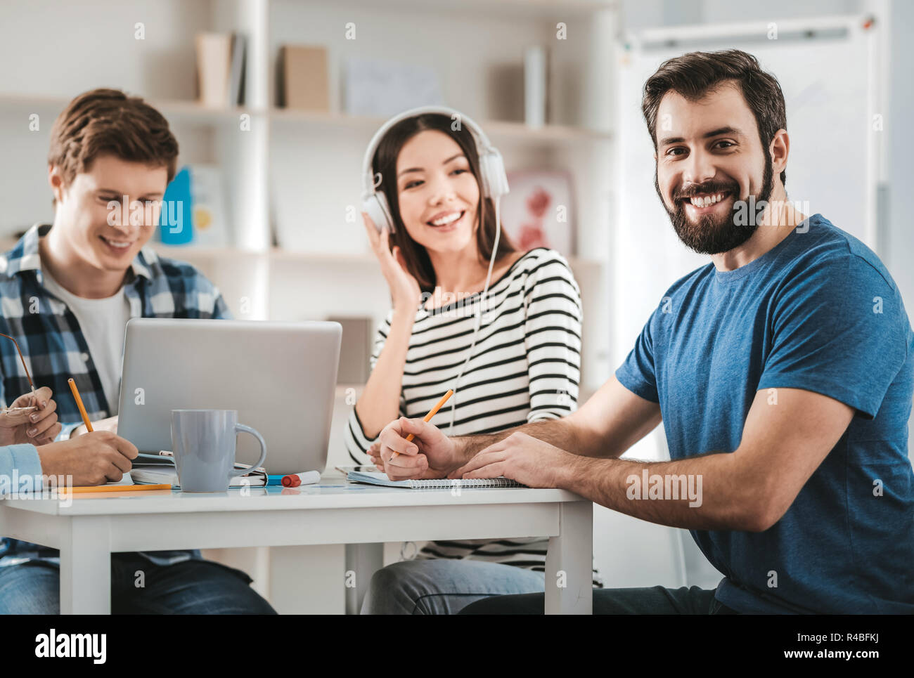 Beautiful colleague. Smiling bearded man wearing blue shirt sitting ...