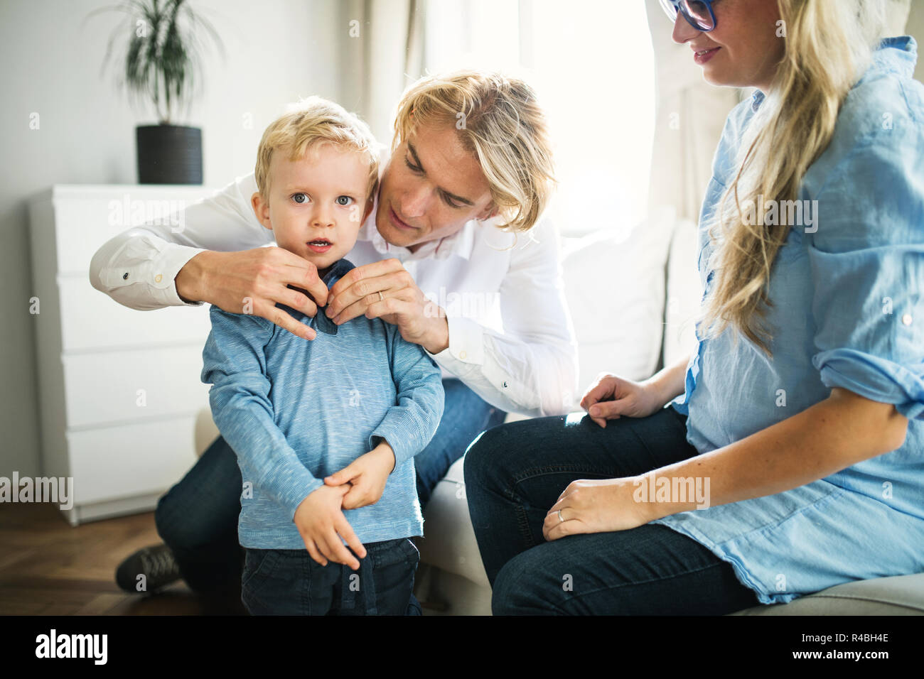 Young parents dressing their toddler son inside in a bedroom Stock ...