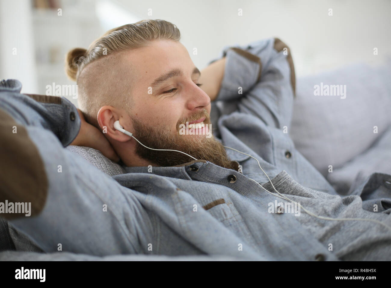 Young man relaxing in sofa, listening to music Stock Photo - Alamy