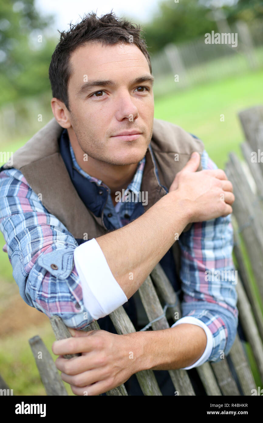 Man in countryside leaning on fence Stock Photo - Alamy