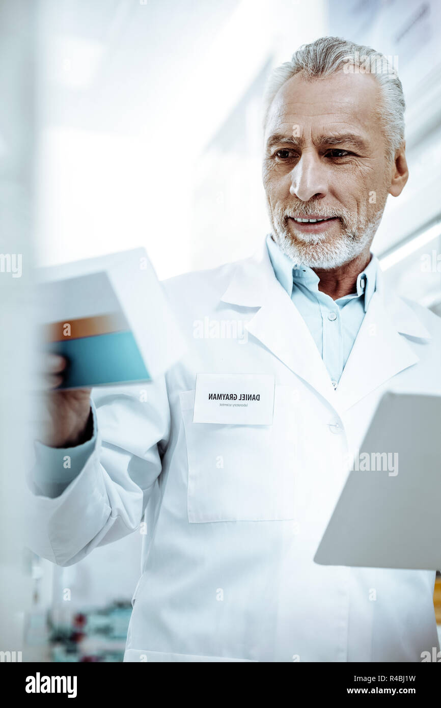 Emotional worker. Kind pharmacist keeping smile on his face while ...