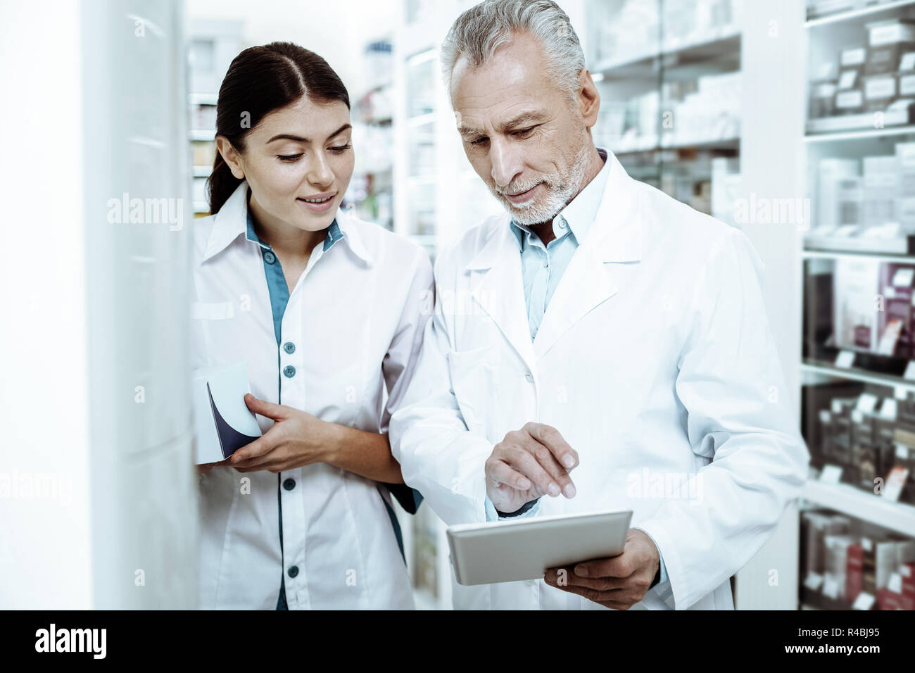 Useful information. Pleased girl wearing medical uniform while working ...