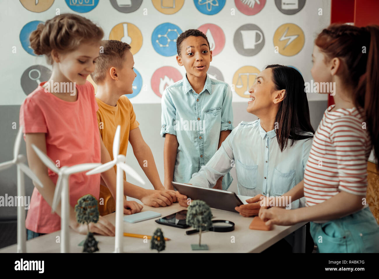 Collective mood. Joyful tutor holding tablet in both hands while ...