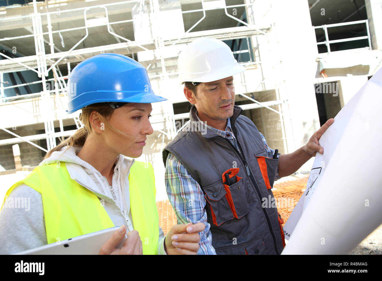Engineers on building site checking plans Stock Photo - Alamy