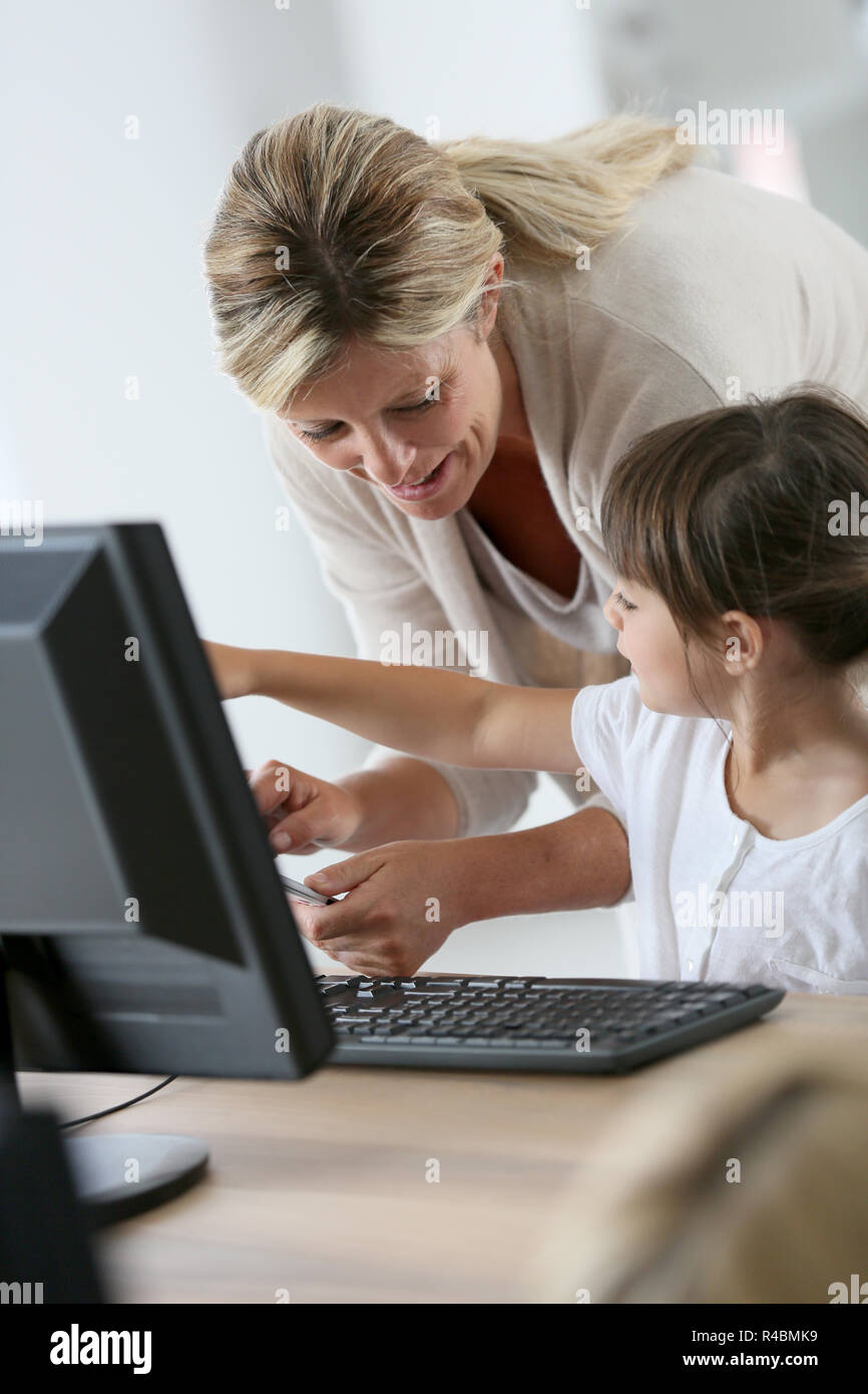 Teacher with little girl in class using computer and tablet Stock Photo ...