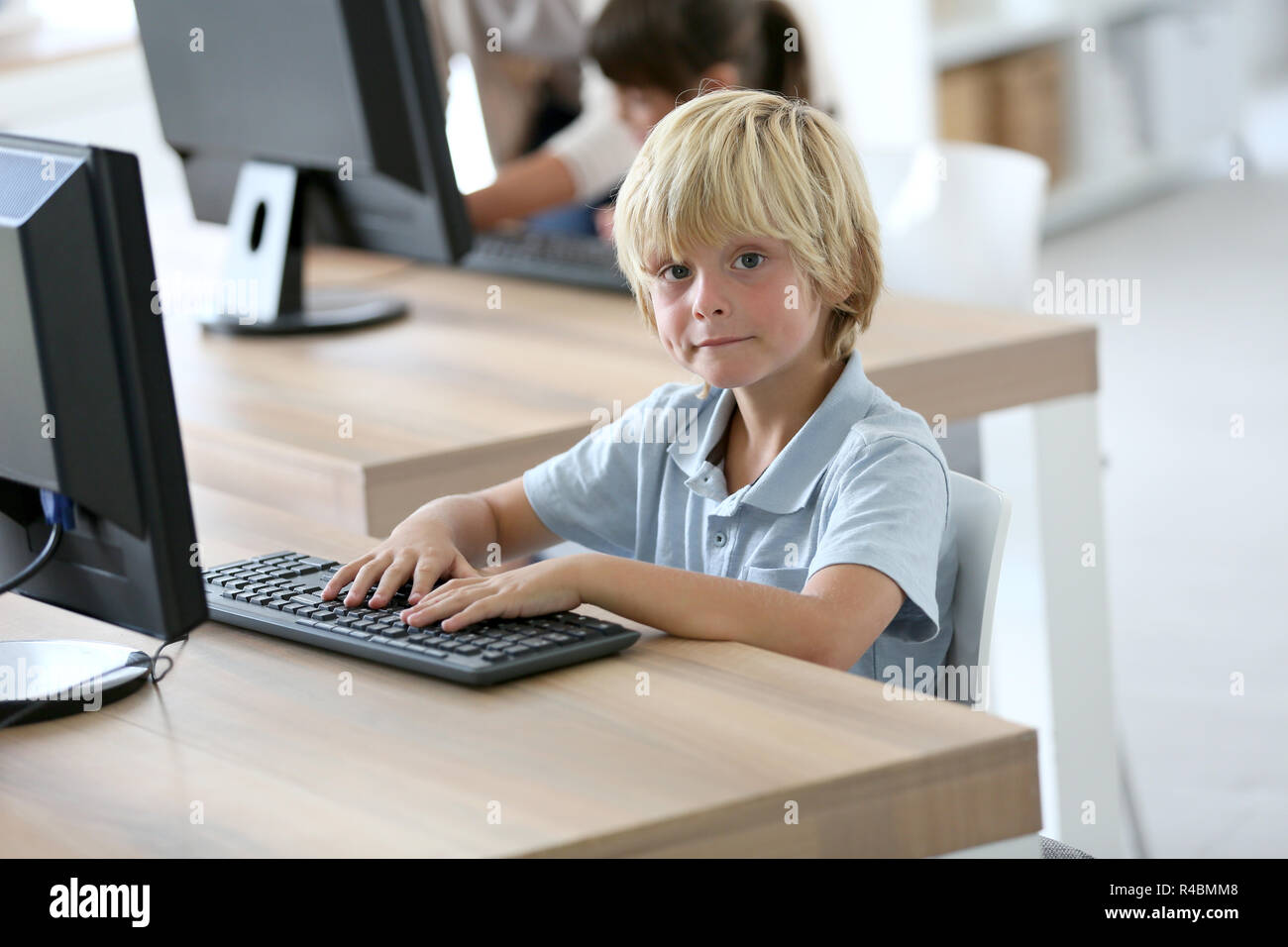 Portrait of school boy sitting in front of computer Stock Photo - Alamy