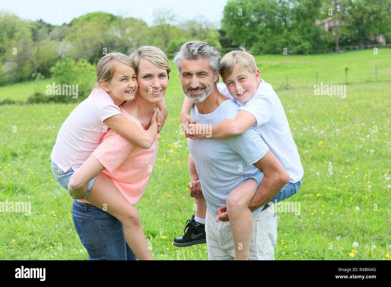 Parents giving piggyback ride to kids in countryside Stock Photo - Alamy