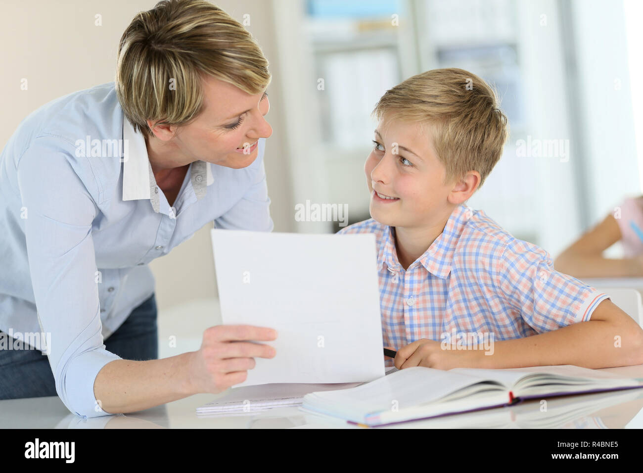 Teacher showing paper to pupil in class Stock Photo - Alamy