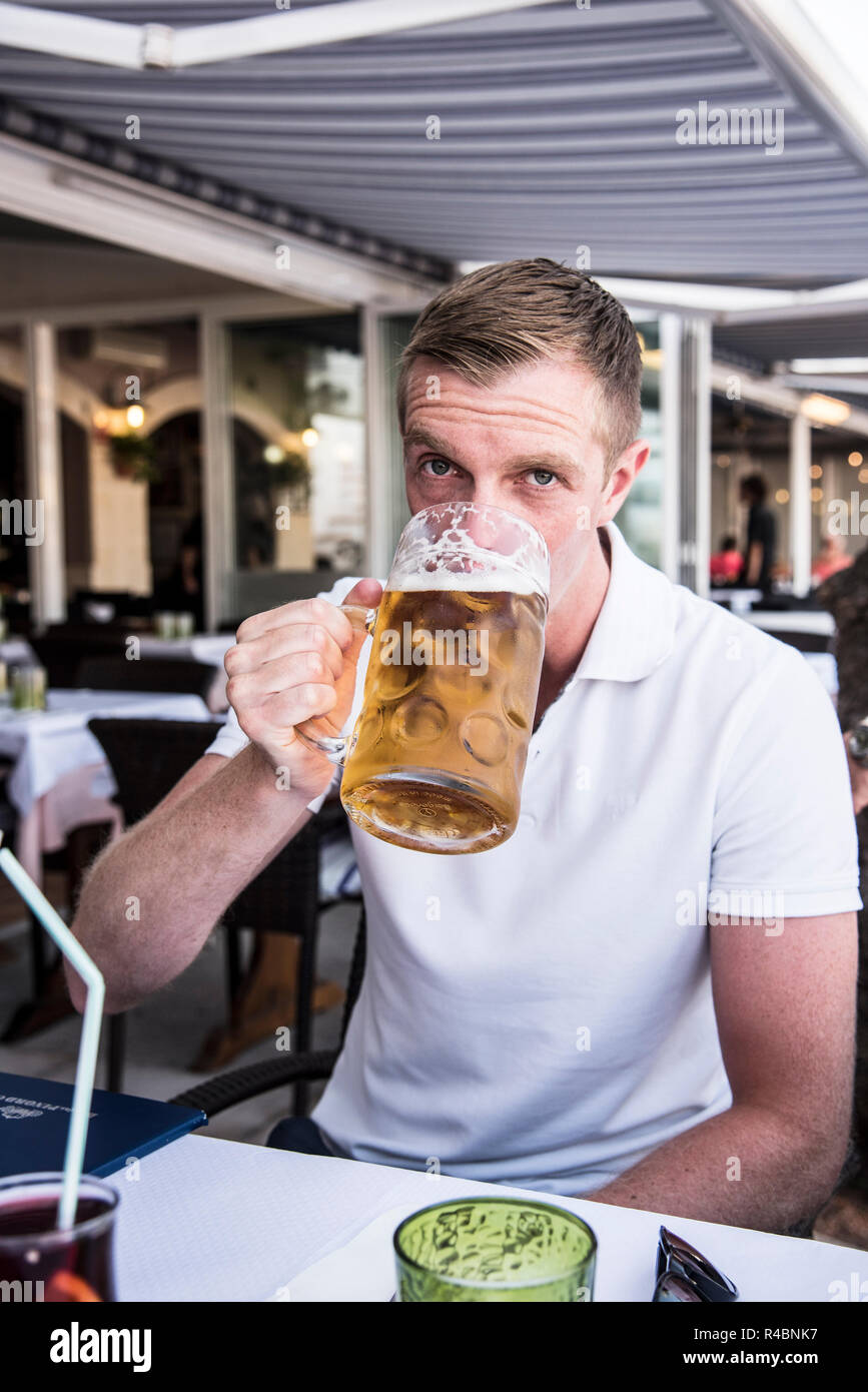 Young man enjoying drinking a large glass of cool lager. Menorca Stock ...