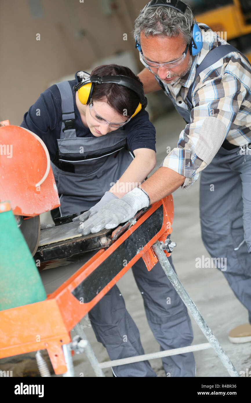 Tiler showing apprentice how to use thermal grinder Stock Photo - Alamy