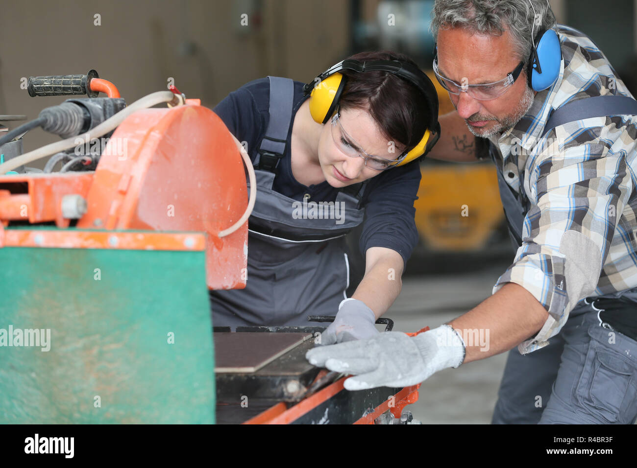 Tiler showing apprentice how to use thermal grinder Stock Photo - Alamy