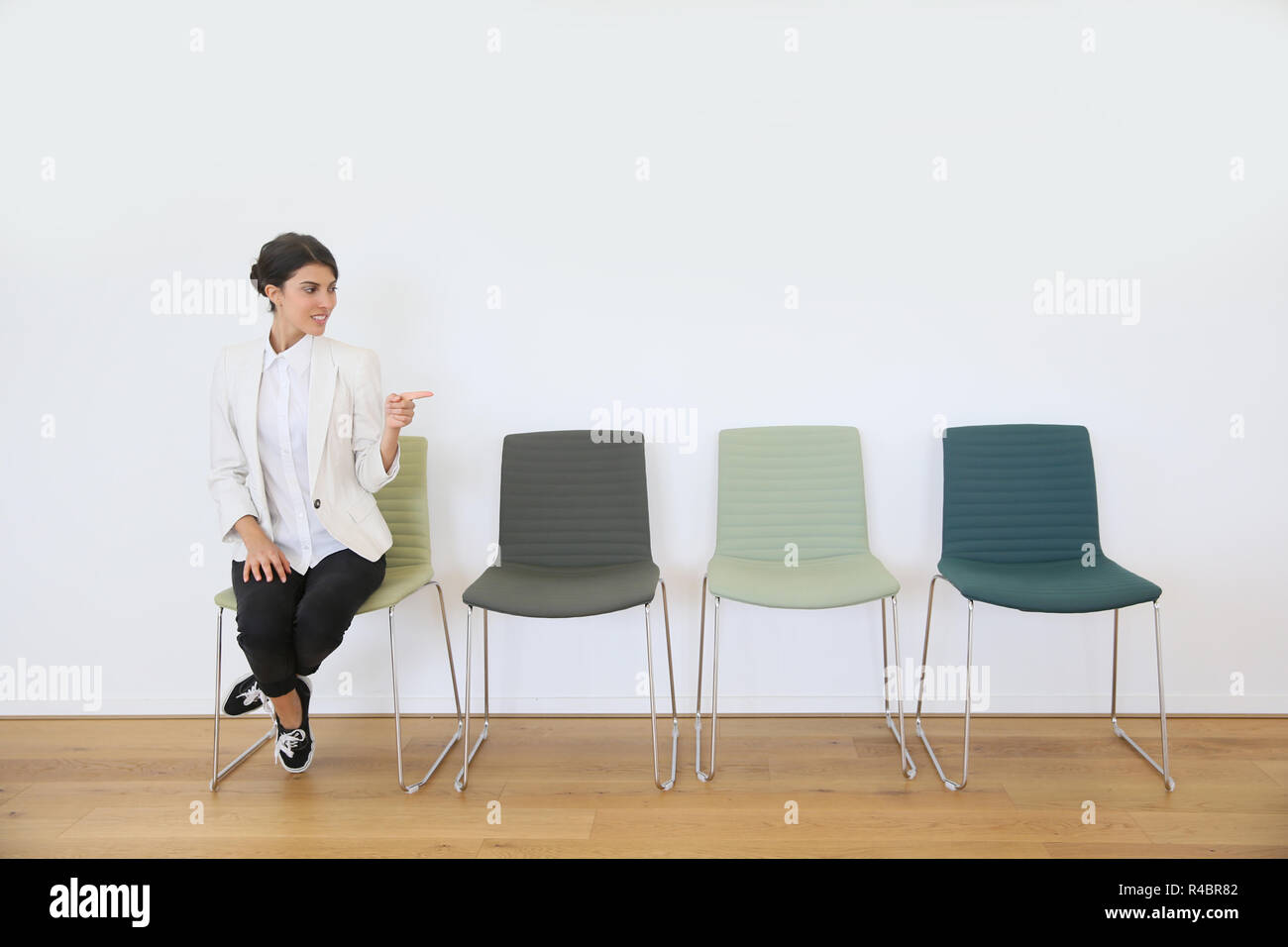 Brunette girl sitting on chair pointing at message Stock Photo - Alamy