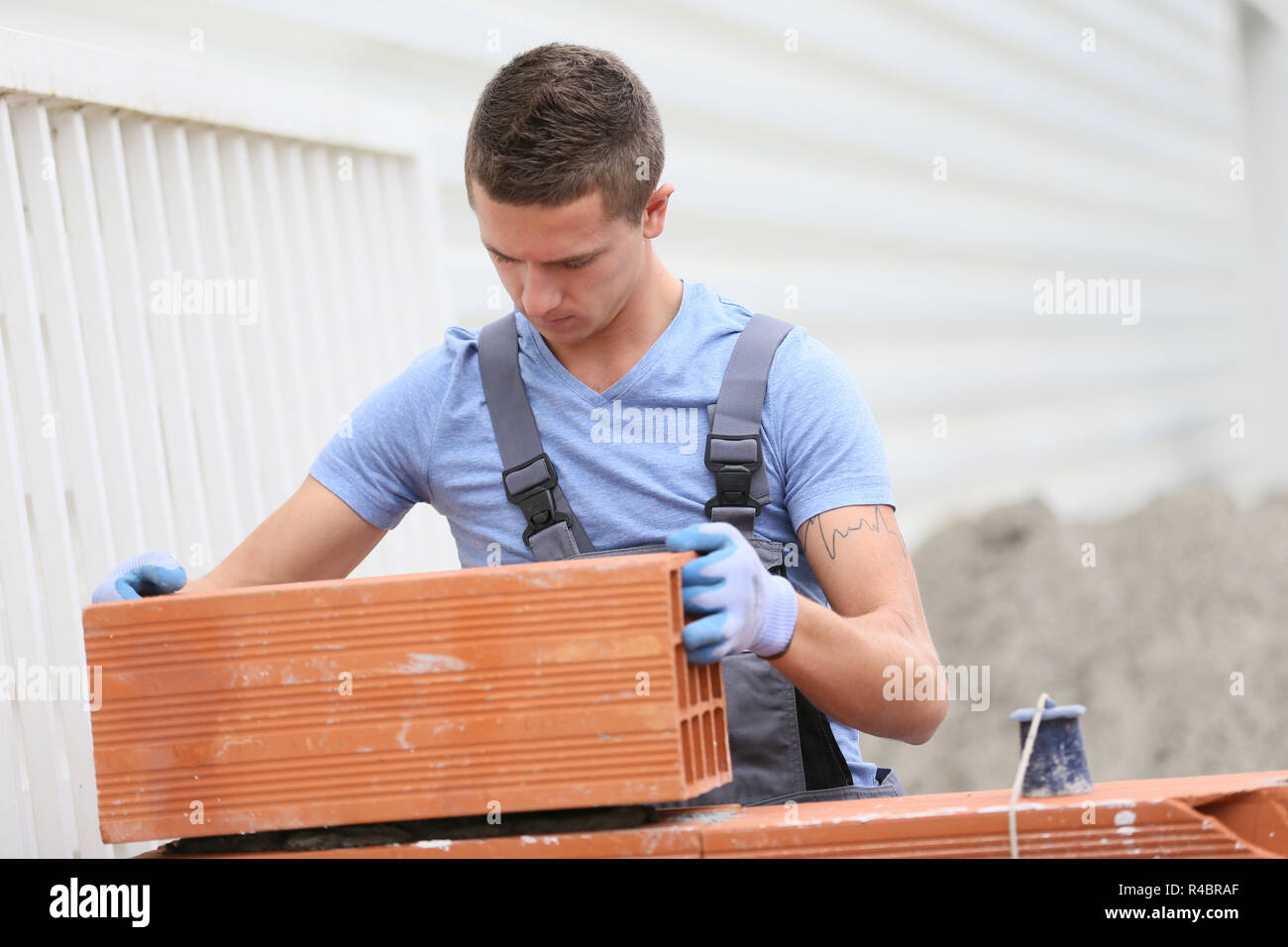 Young brick layer working outside on brick wall construction Stock ...