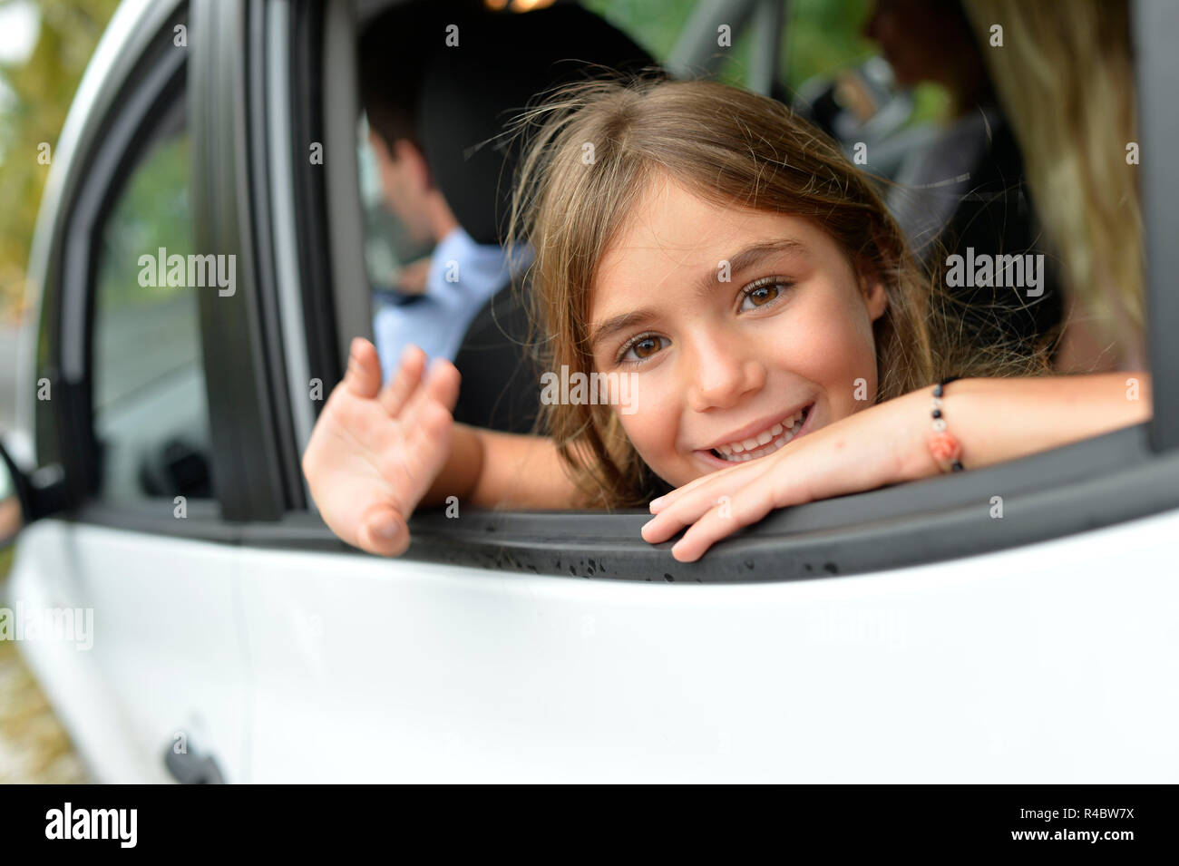 Little girl waving hand by car window Stock Photo - Alamy
