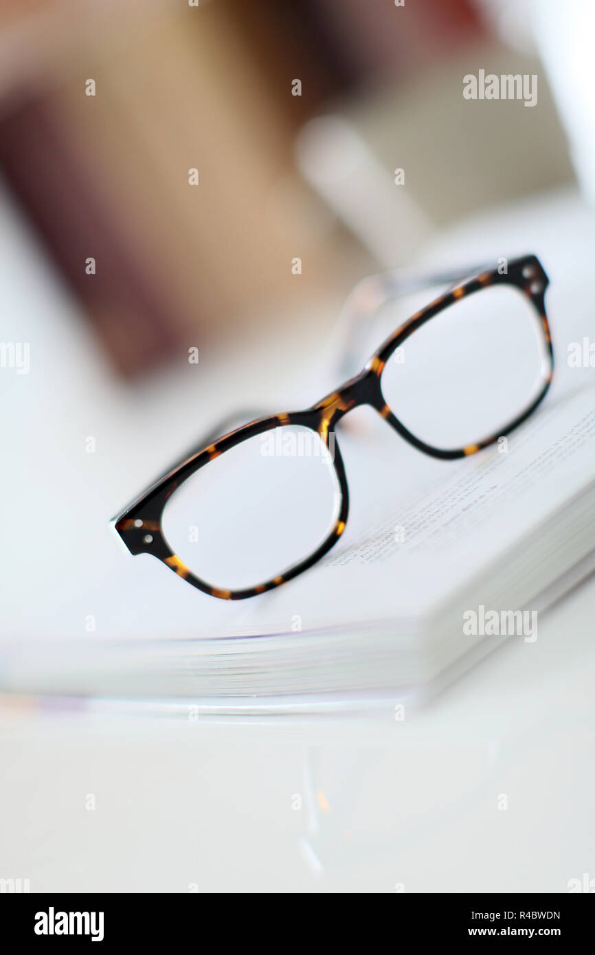 Eyeglasses laid over book on table Stock Photo - Alamy