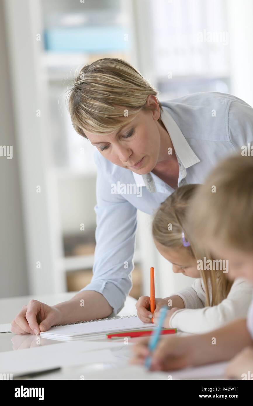Teacher helping kids in classroom Stock Photo - Alamy