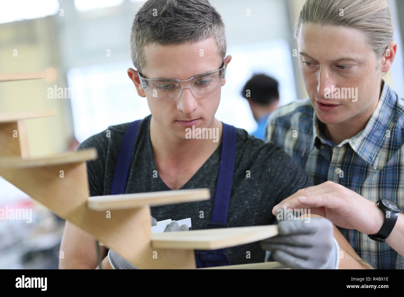 Apprentice with adult in carpentry school working on wood Stock Photo ...