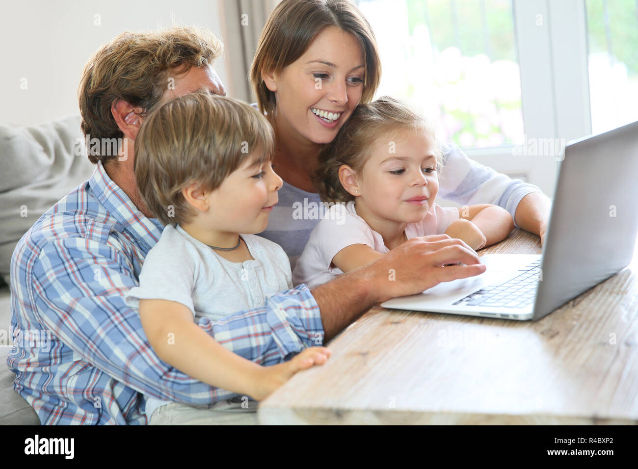 Parents with kids at home using laptop computer Stock Photo - Alamy