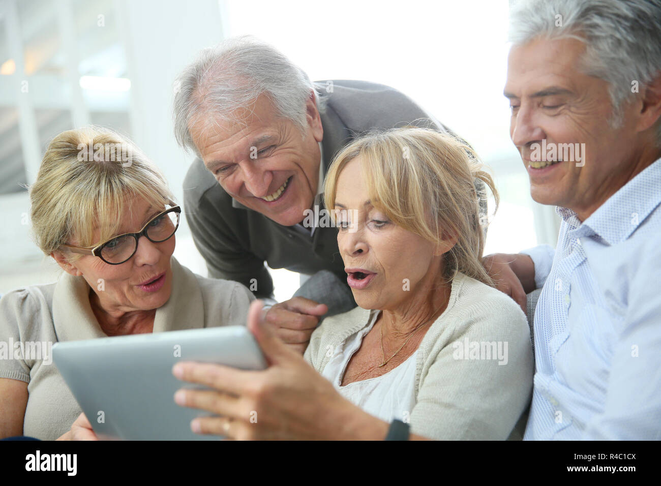Group of retired people sitting in sofa and using tablet Stock Photo ...