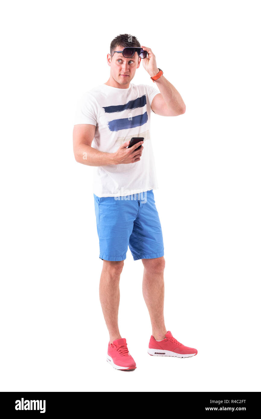 Cool handsome confused man holding sunglasses and cellphone looking ...