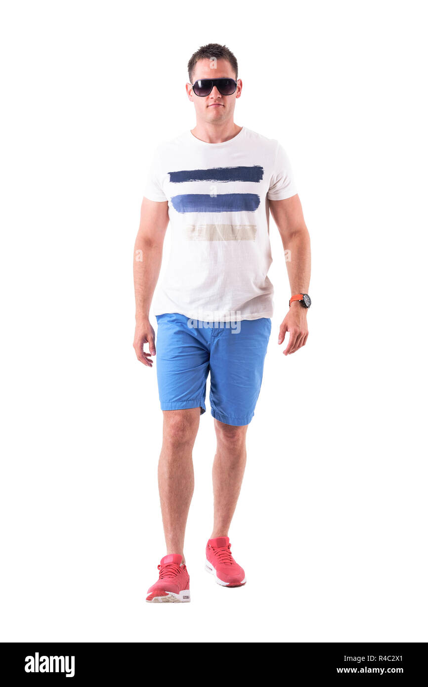 Tough serious man walking towards camera in summer leisurewear. Full ...