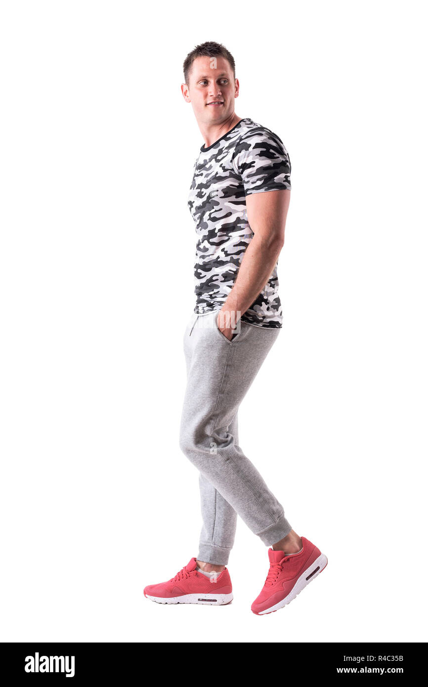 Happy macho sporty young man walking, smiling and looking back. Side ...