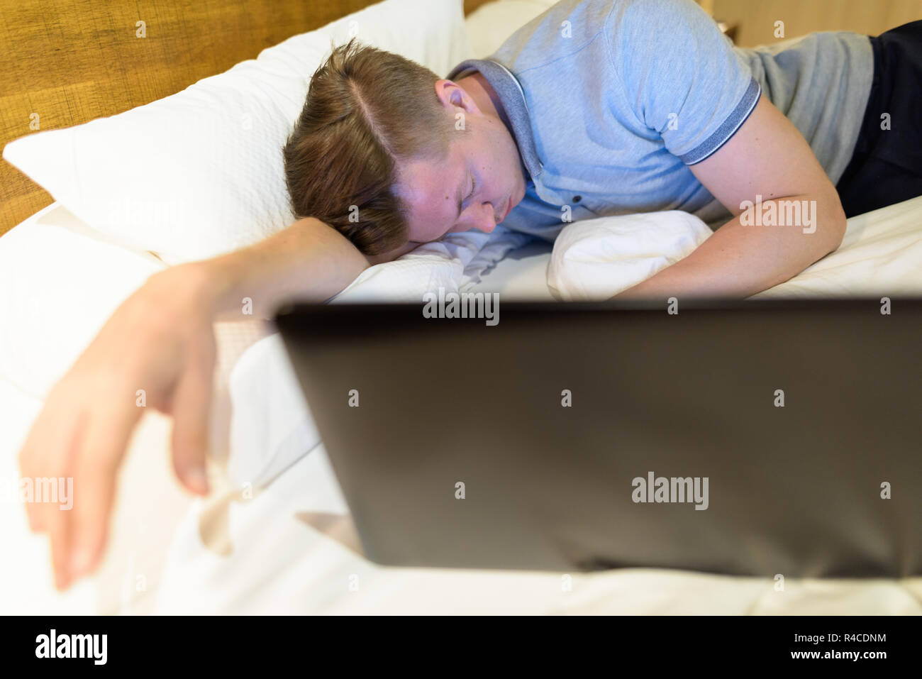 Overworked man using laptop while sleeping in bedroom Stock Photo - Alamy