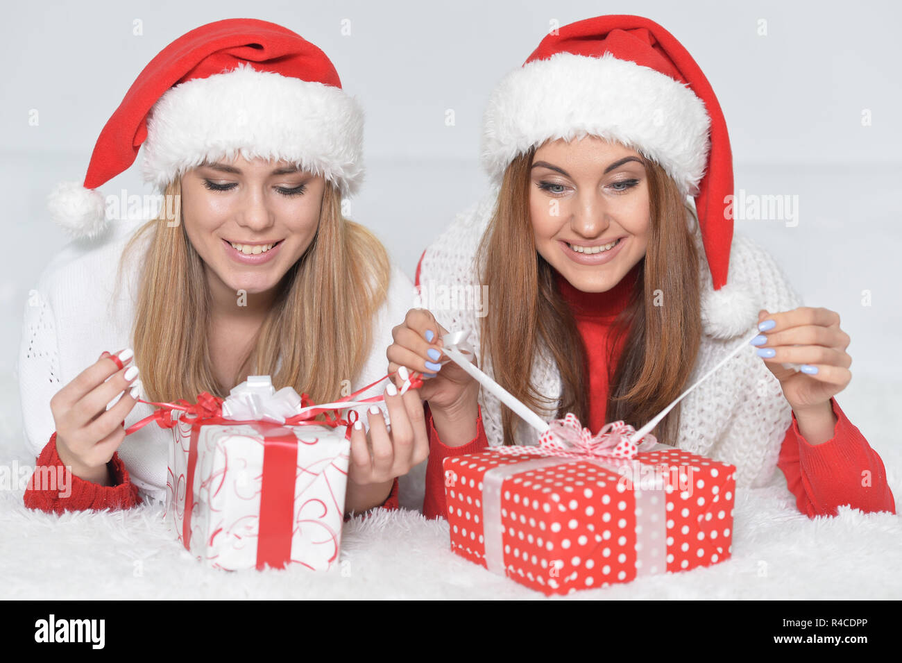 Two beautiful women opening Christmas presents Stock Photo - Alamy