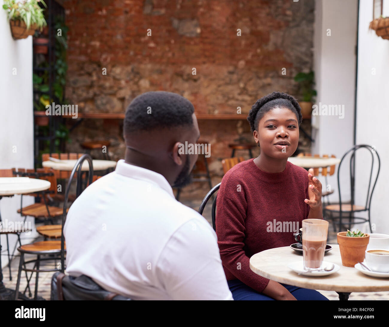 Two friends talking over drinks in a trendy cafe courtyard Stock Photo ...