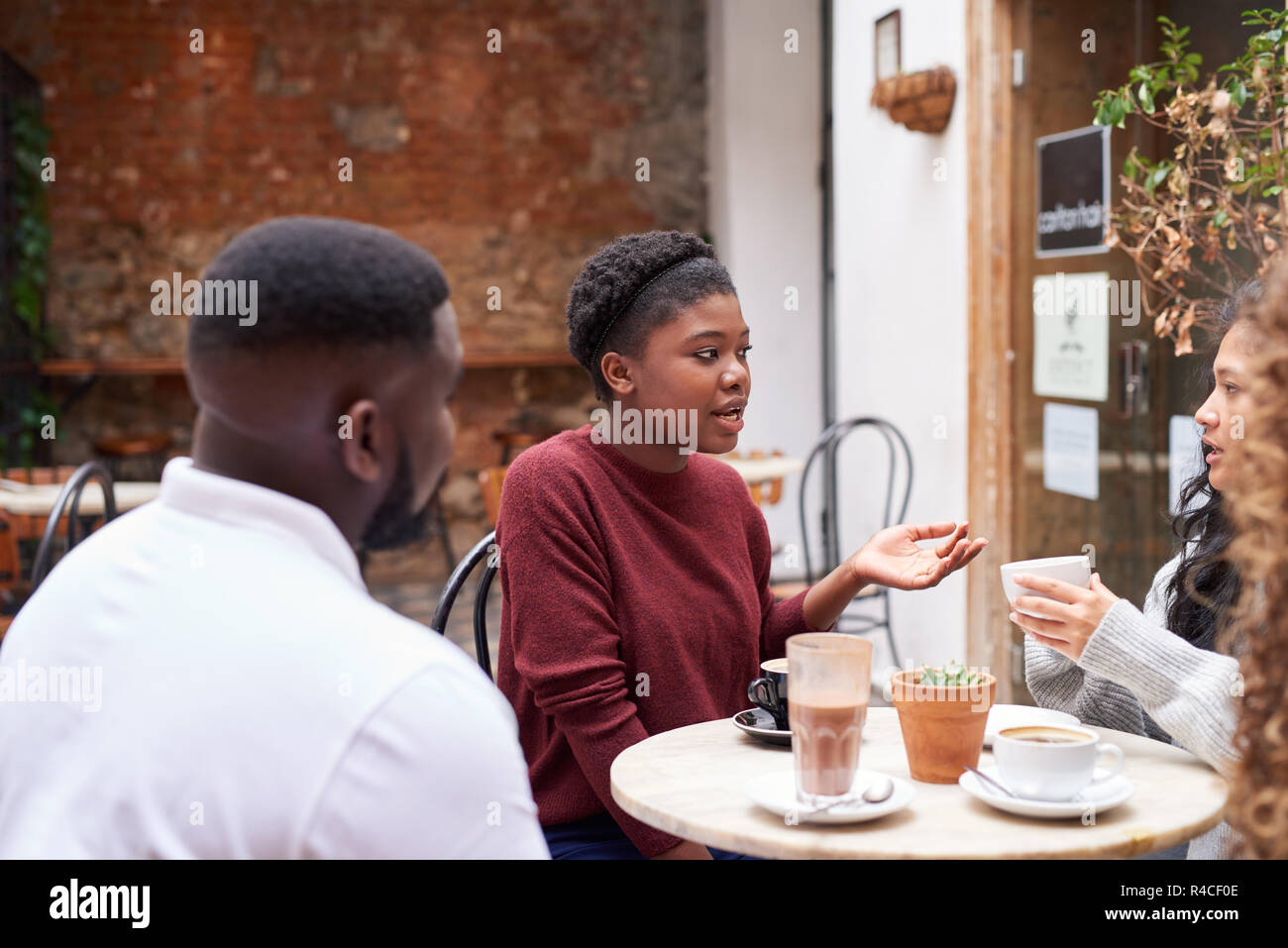 Diverse friends talking over drinks in a trendy cafe courtyard Stock ...
