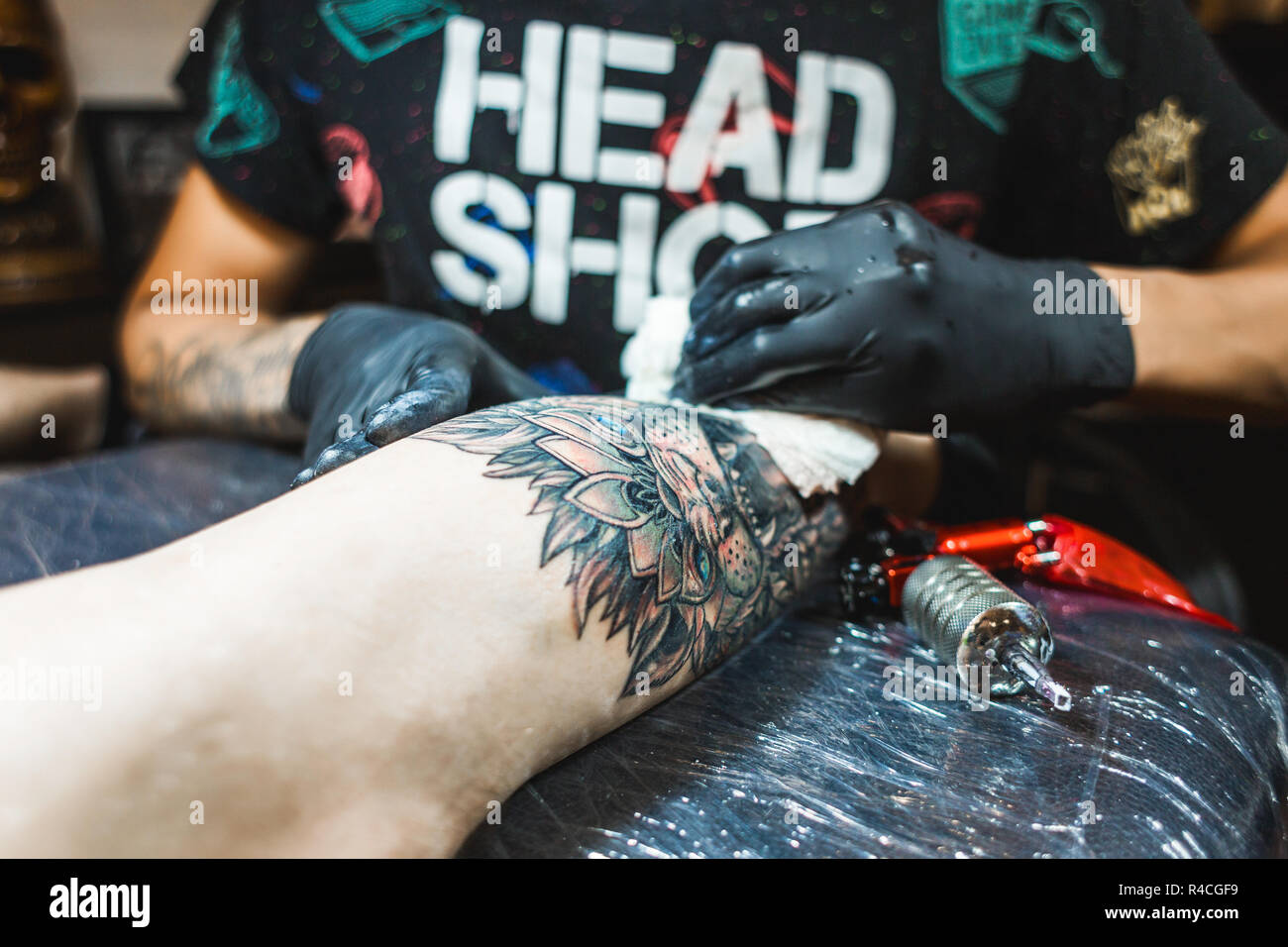 The tattoo artist creates a picture on the body of a man. close-up of ...