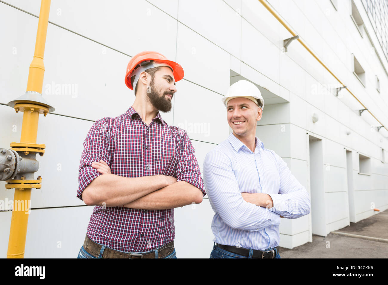 two male engineers in helmets on the building background Stock Photo ...