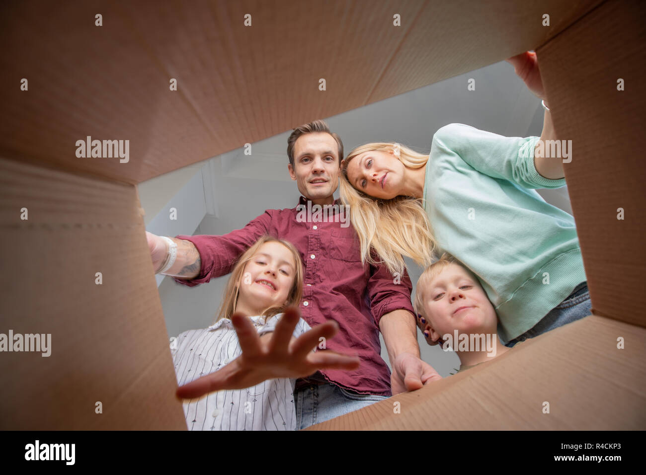 Photo of cheerful parents and children looking inside cardboard box in ...
