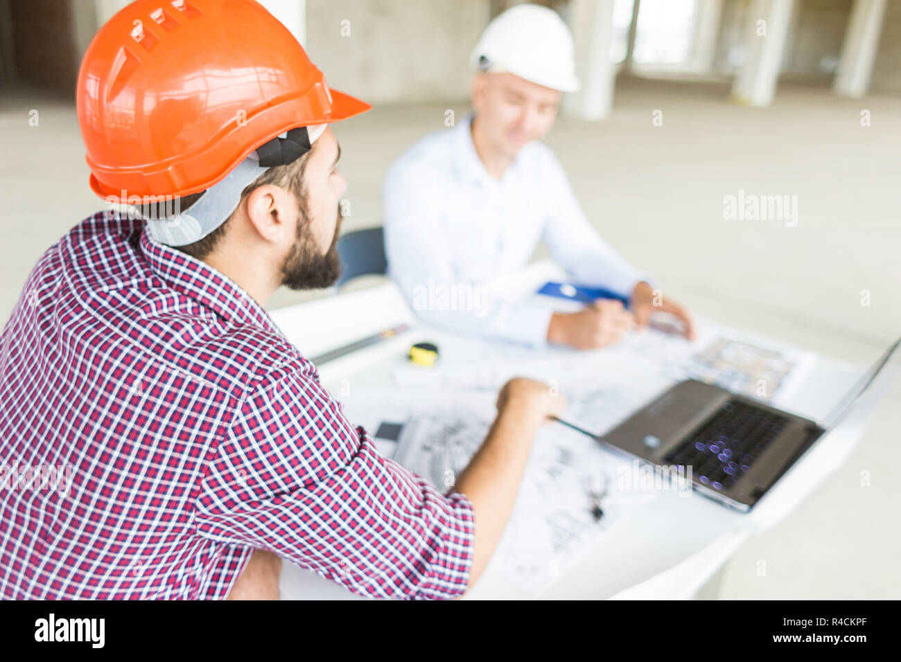 male engineers, architects working at the desk in helmets. Drawings ...
