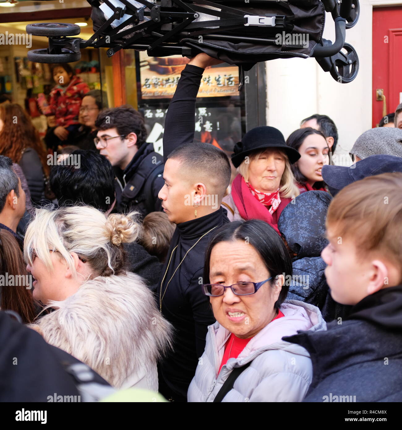 Man carries childs push chair through crowd in Chinatown, Soho, London ...