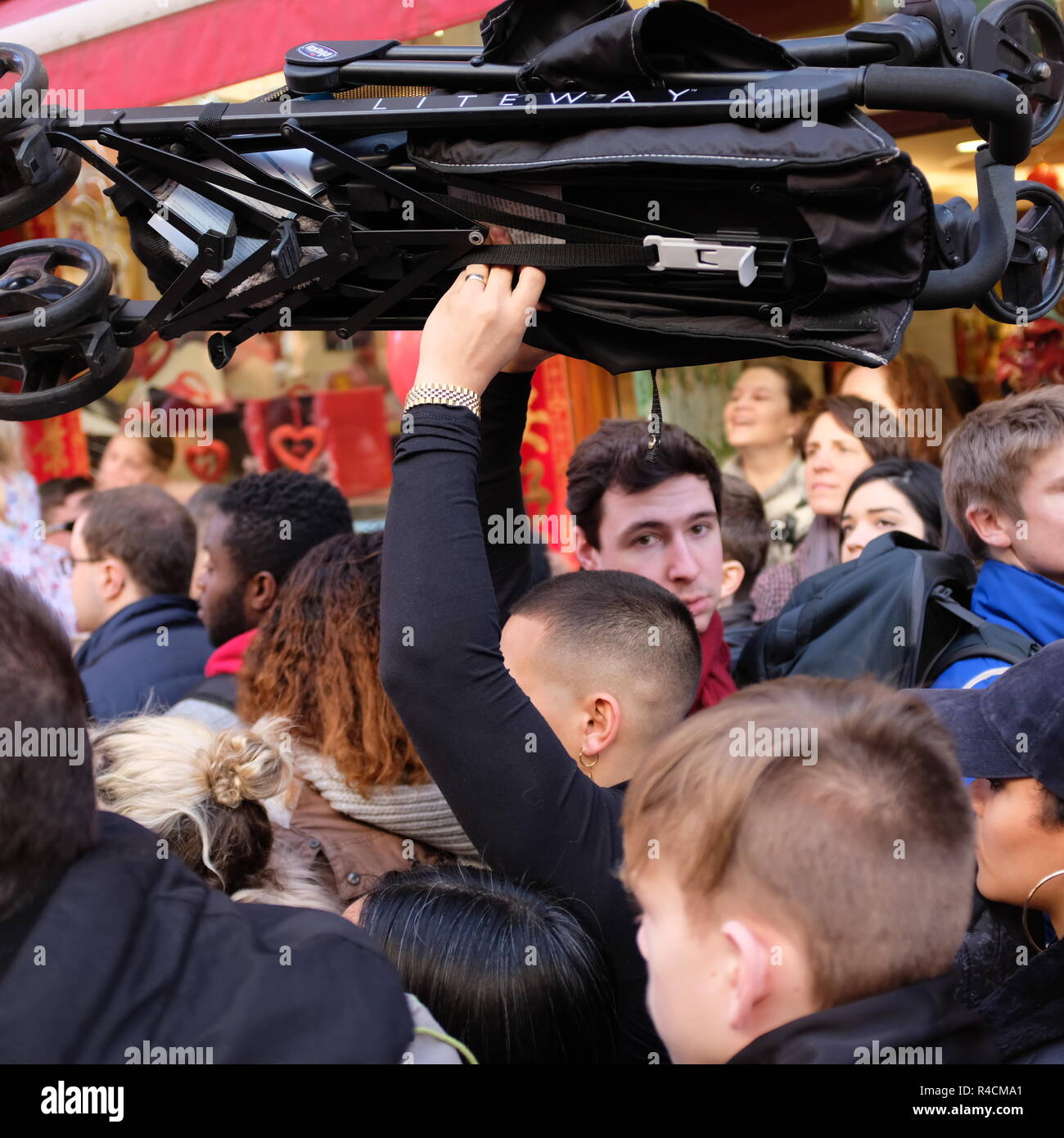 Man carries childs push chair through crowd in Chinatown, Soho, London ...