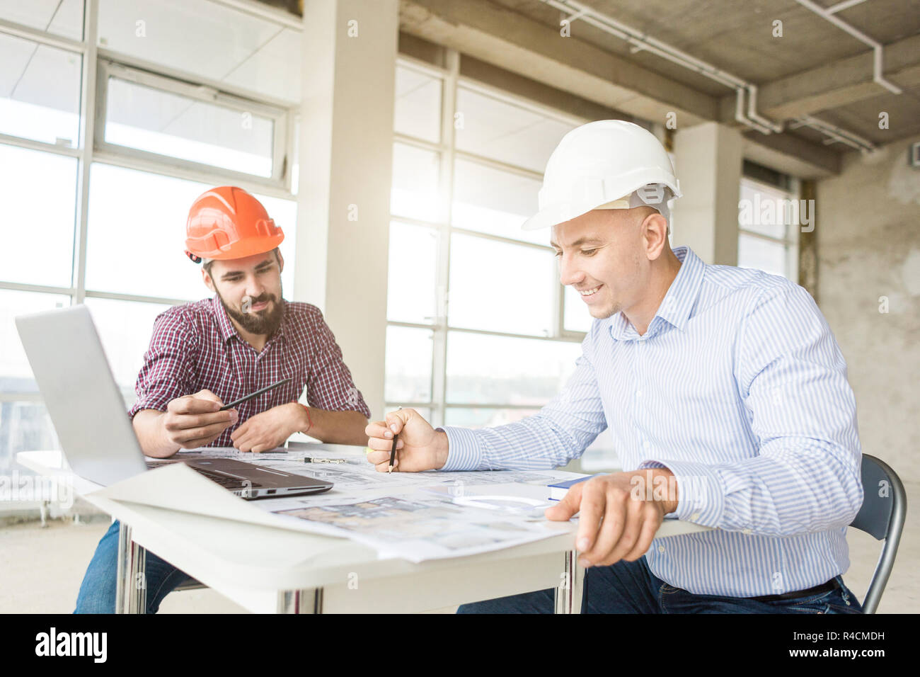 male engineers, architects working at the desk in helmets. Drawings ...