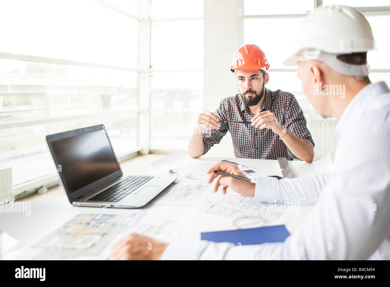 male engineers, architects working at the desk in helmets. Drawings ...