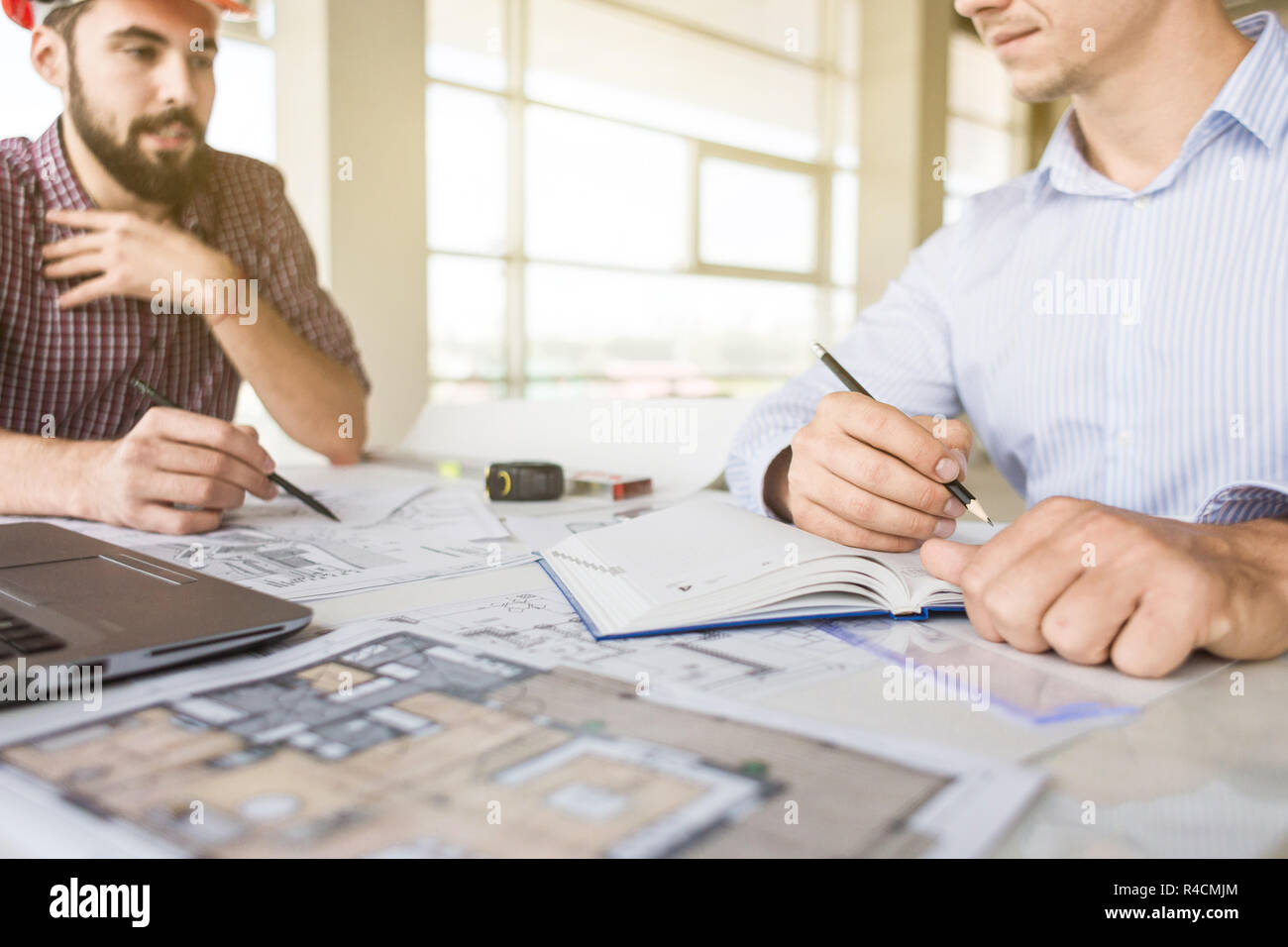male engineers, architects working at the desk in helmets. Drawings ...