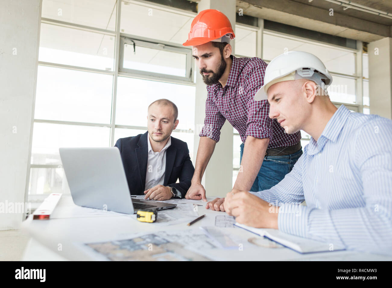 male engineers, architects working at the desk in helmets. Drawings ...