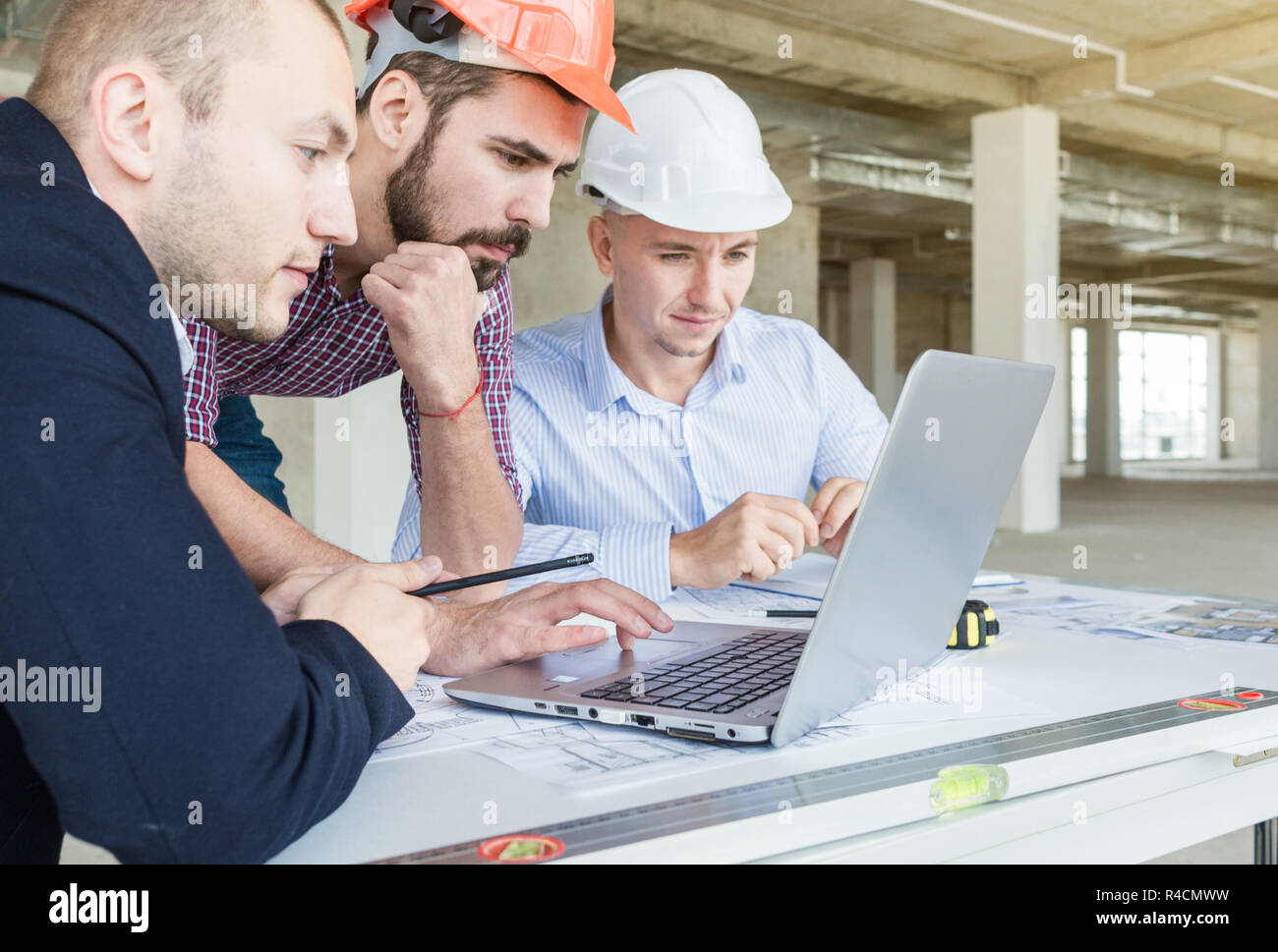 male engineers, architects working at the desk in helmets. Drawings ...